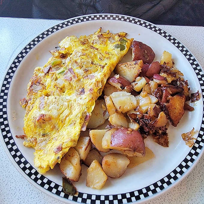 A properly executed omelet is culinary poetry. This golden creation, paired with a mountain of home fries, is breakfast harmony on a plate.