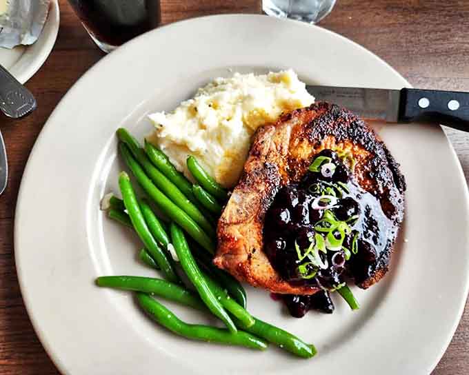 A pork porterhouse glazed to perfection, proving that sometimes the best things in life come with a side of green beans.