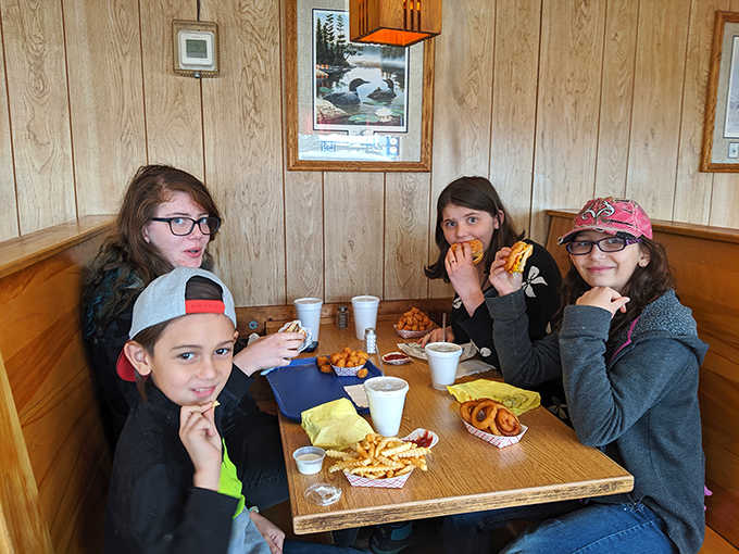 Four young diners enjoying the timeless pleasure of comfort food in a wooden booth&mdash;creating memories that will outlast whatever's on their phones.