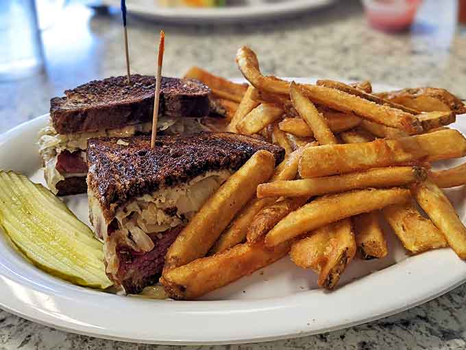 A Reuben sandwich built like it means business, with enough fries to make sharing optional but recommended. The pickle stands guard against sandwich thieves.