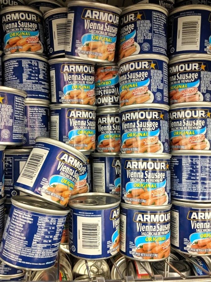 Vienna sausages stacked like tiny cylindrical monuments to practicality. Apocalypse preppers and midnight snackers unite over these protein-packed tubes.