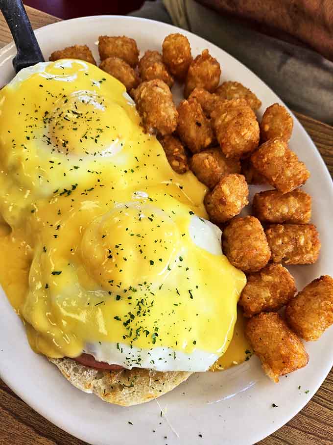 Eggs Benedict with hollandaise so sunny it could brighten even the gloomiest Monday, paired with golden tater tots that crunch like autumn leaves.