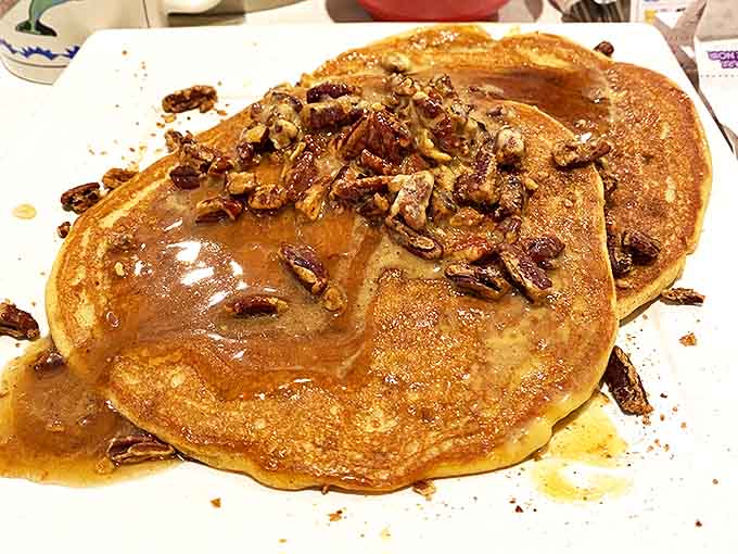 Pancakes that have clearly been taking steroids—golden, fluffy discs topped with candied pecans that make maple syrup seem like the supporting actor.