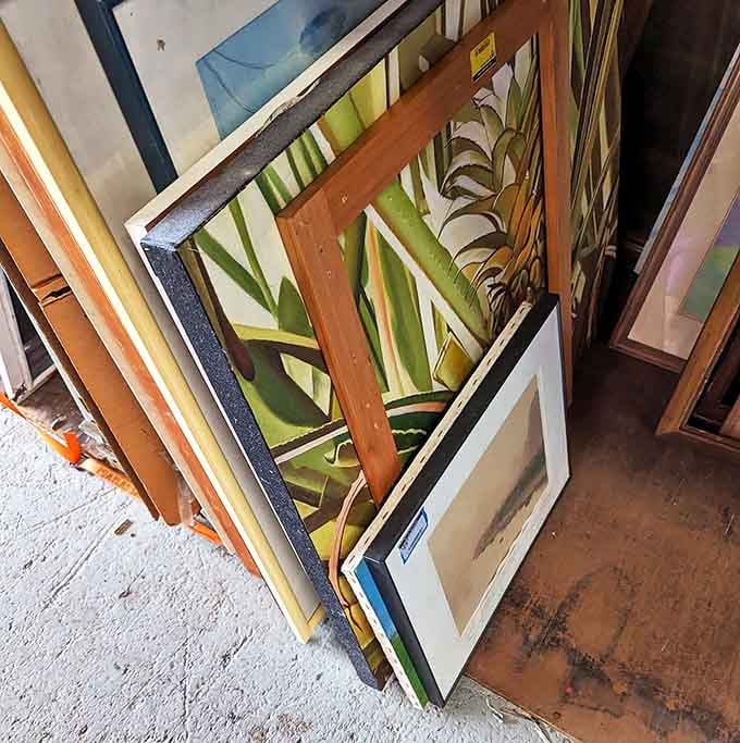 Art and frames lean casually against each other like old friends at a reunion, waiting for new walls to call home.