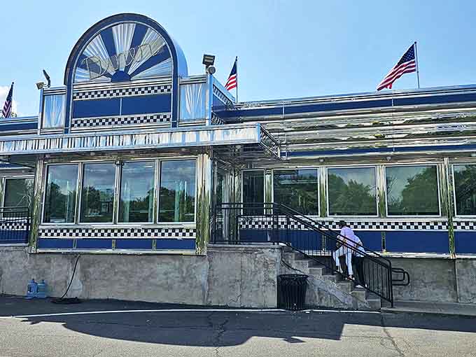 Sunlight dances across the Blue Colony's classic diner architecture. American flags flutter above this temple of pancakes and patty melts.