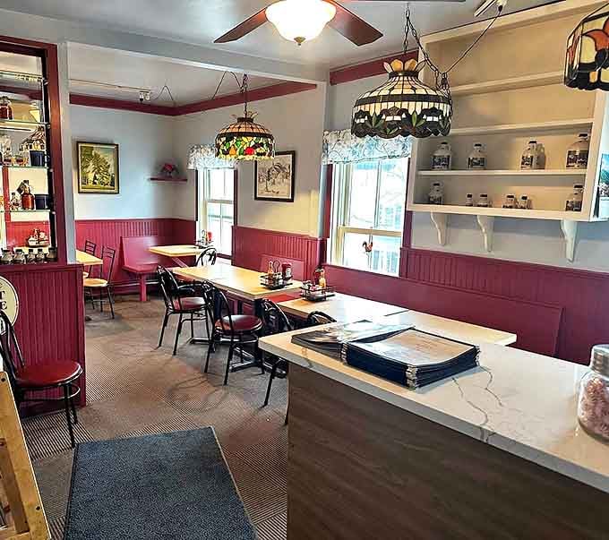 Tiffany-style lamps cast a warm glow over cranberry wainscoting, creating the kind of cozy Vermont breakfast nook that makes you want to linger all morning.