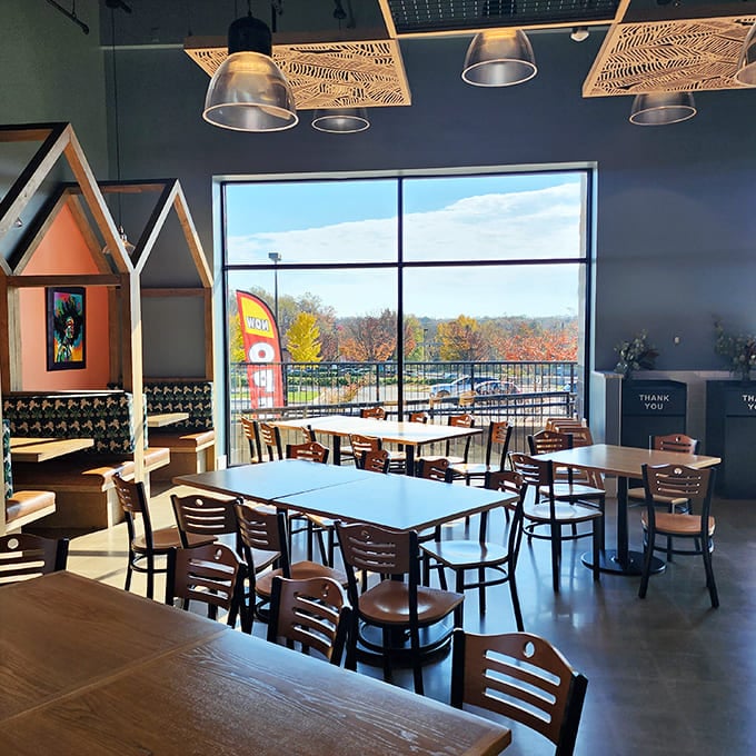 Sunlight floods through floor-to-ceiling windows, illuminating a dining room where contemporary design meets Southern hospitality. Those house-shaped booths? Pure genius.