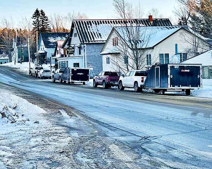 Winter transforms Rangeley into a snow globe come to life, where pickup trucks and trailers stand ready for adventures in Maine's frosty playground.