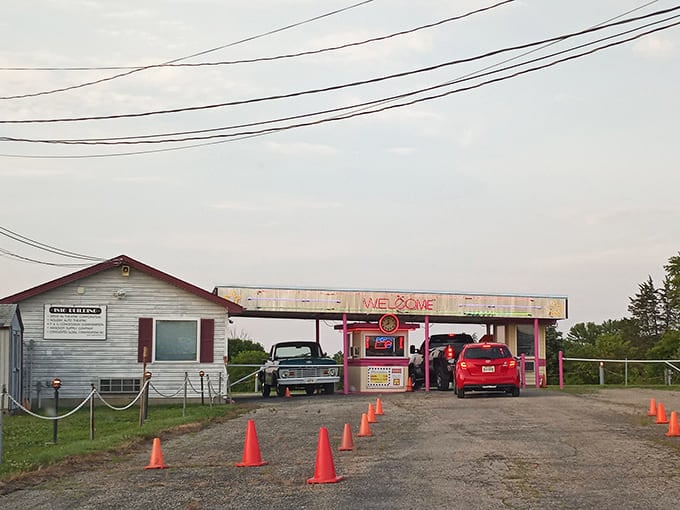 The retro welcome booth stands like a time machine, orange cones guiding modern cars into a slice of Americana that refuses to fade.
