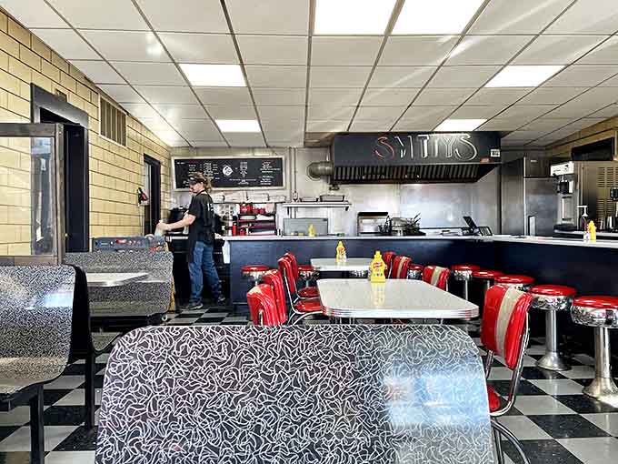 Classic diner aesthetics never go out of style. The black and white checkered floor and red vinyl seats promise comfort food paradise awaits.
