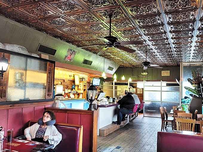 That ornate tin ceiling isn't showing off; it's just quietly adding character while red vinyl booths invite you to slide in and stay awhile.