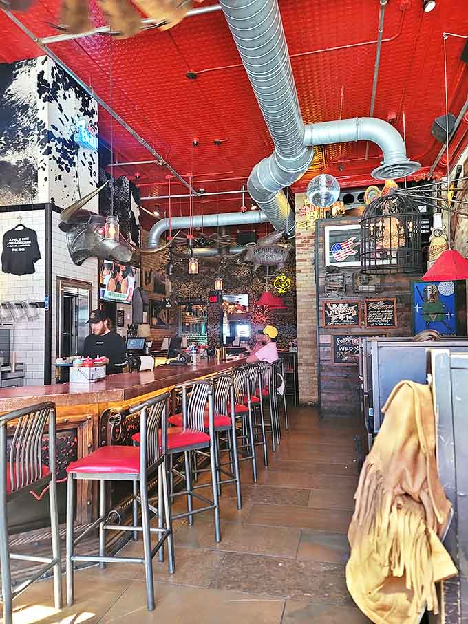 That striking red ceiling and industrial ductwork create the perfect backdrop for barbecue alchemy. Notice the bar seating—front row tickets to the show.