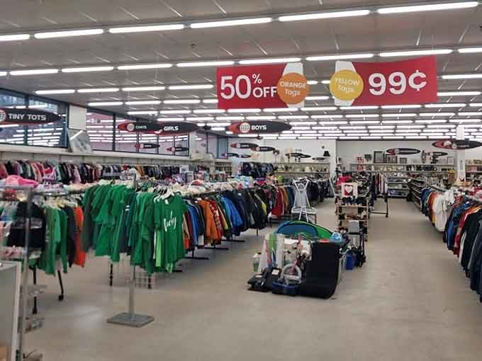 A treasure hunter's paradise unfolds under fluorescent lights, where color-coded racks create a rainbow roadmap to secondhand glory.