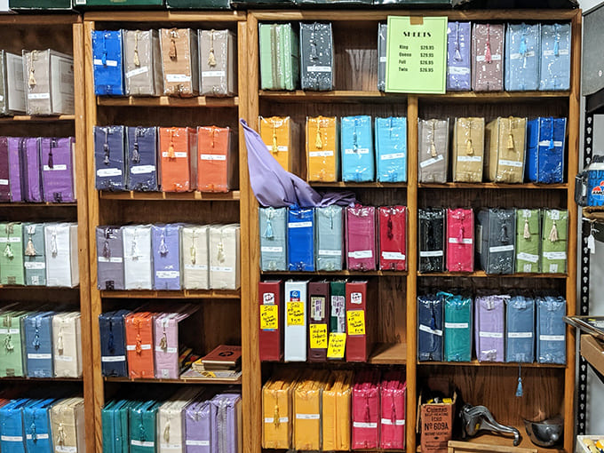 A rainbow of sheets stands at attention like soldiers from another era, each one holding the promise of comfort and memorable moments.