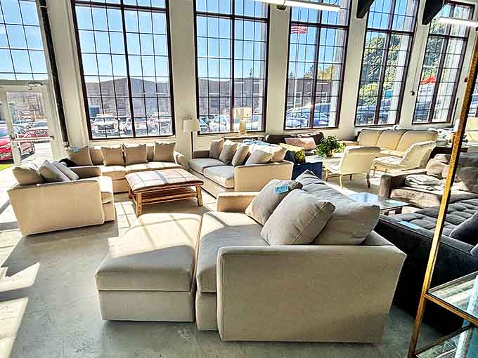 Sunlight floods through warehouse windows, illuminating a sea of neutral-toned sofas that look ready for their second act in someone's living room.