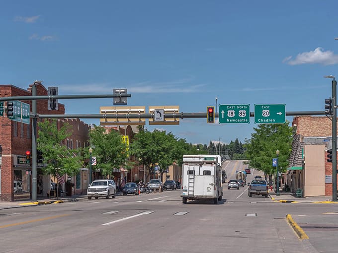 Main street intersection in Lusk, Wyoming, with highway signs pointing to Newcastle and Chadren under clear blue skies.