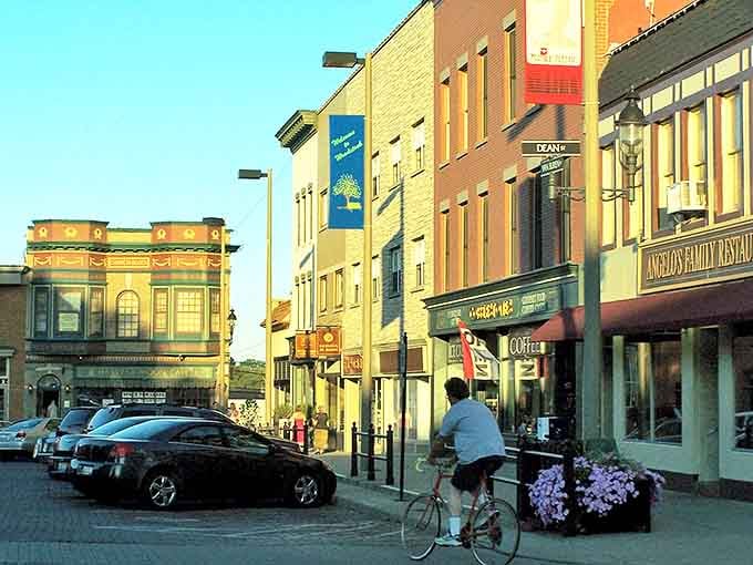 Golden hour light kisses these storefronts where cyclists pedal past restaurants&mdash;small-town living never looked so inviting and warm.