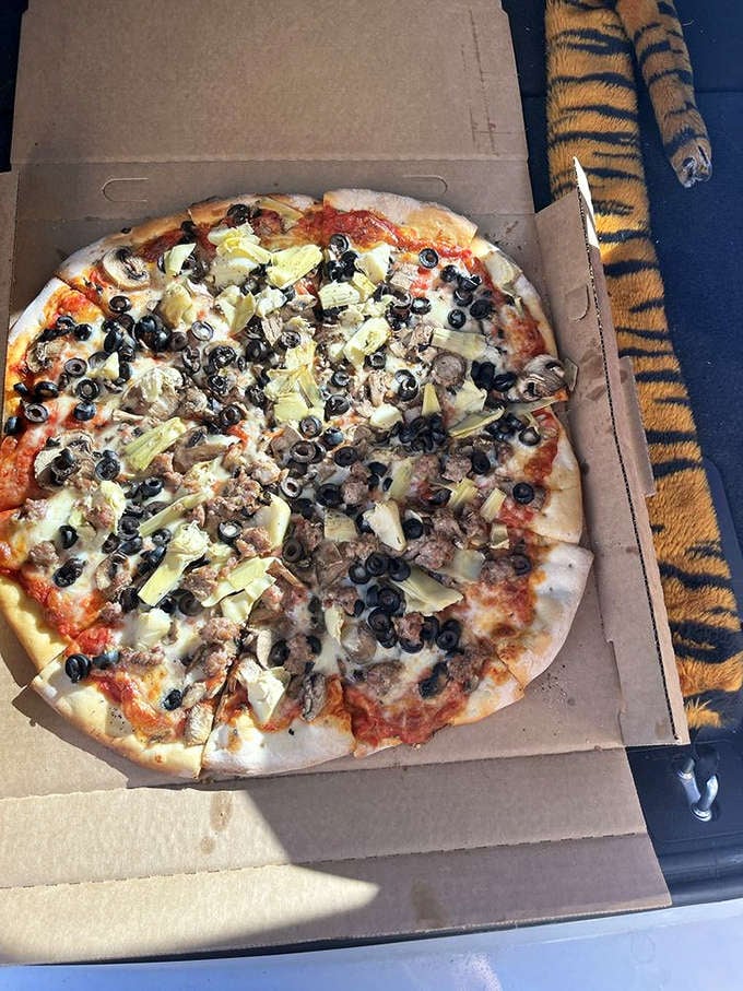 Pizza perfection in its natural habitat: artichoke hearts, black olives, and ground beef playing together in harmony atop that signature Shakespeare's crust.