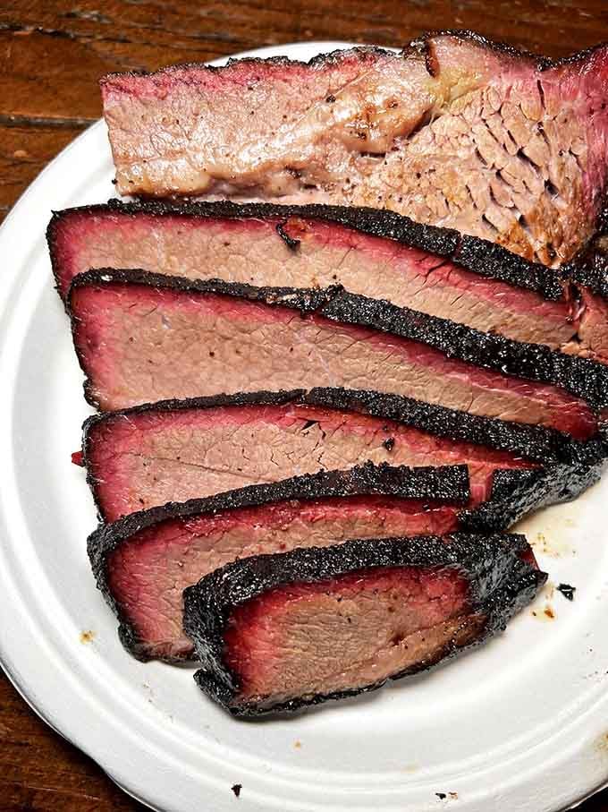Behold the holy grail of Texas BBQ: brisket with that perfect smoke ring and bark that should be considered a national treasure.