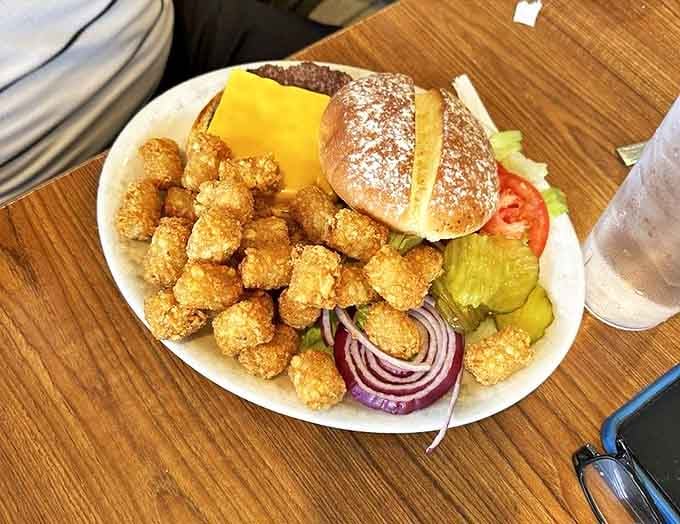 This isn't just a burger&mdash;it's an architectural marvel of crispy tater tots, melted cheese, and fresh veggies that requires both hands and several napkins.