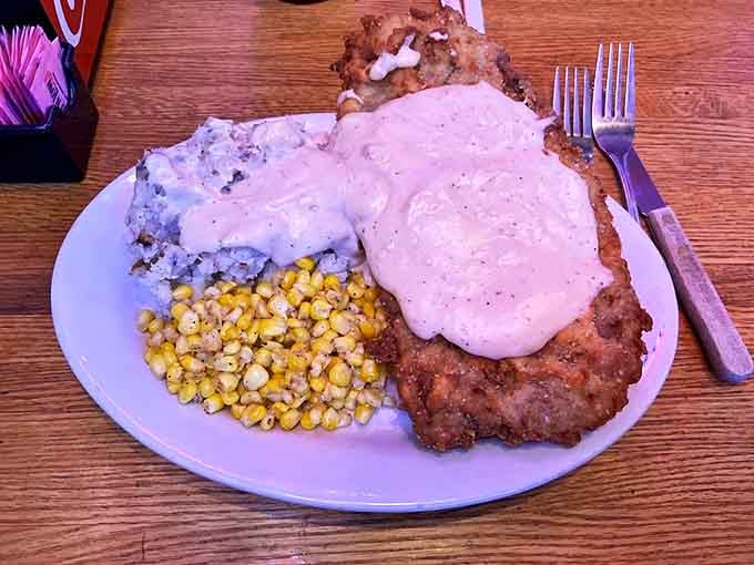 Behold, the star of the show! This chicken fried steak spills over the plate's edges, smothered in peppery cream gravy that would make any Texan weep with joy.