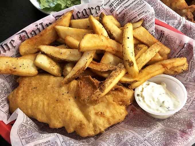 Golden-battered fish resting on a bed of proper chips, served on newspaper&mdash;this isn't just food, it's edible British heritage that crackles with each perfect bite.