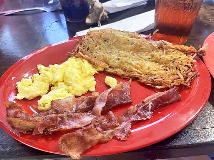 Breakfast perfection on a plate: fluffy scrambled eggs, crispy hash browns with that ideal golden crust, and bacon cooked just right.