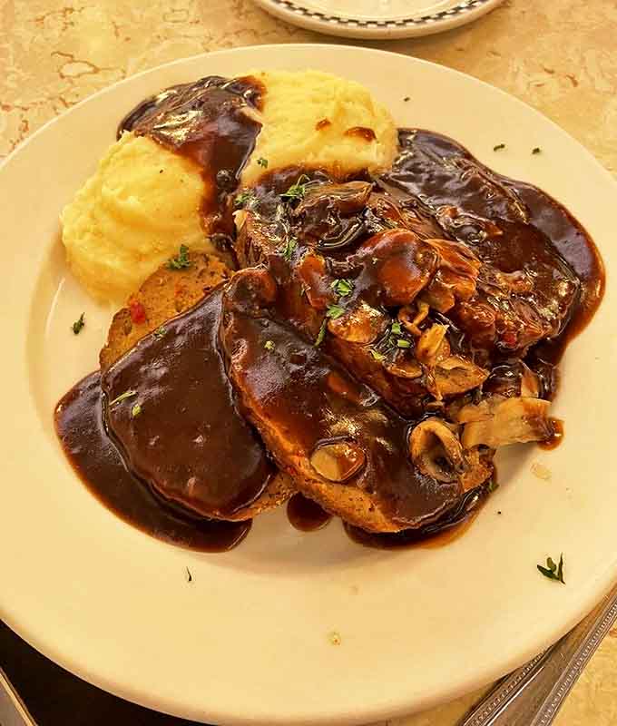 Meatloaf swimming in rich gravy alongside creamy mashed potatoes&mdash;the kind of plate that makes you want to hug the chef and your grandmother simultaneously.