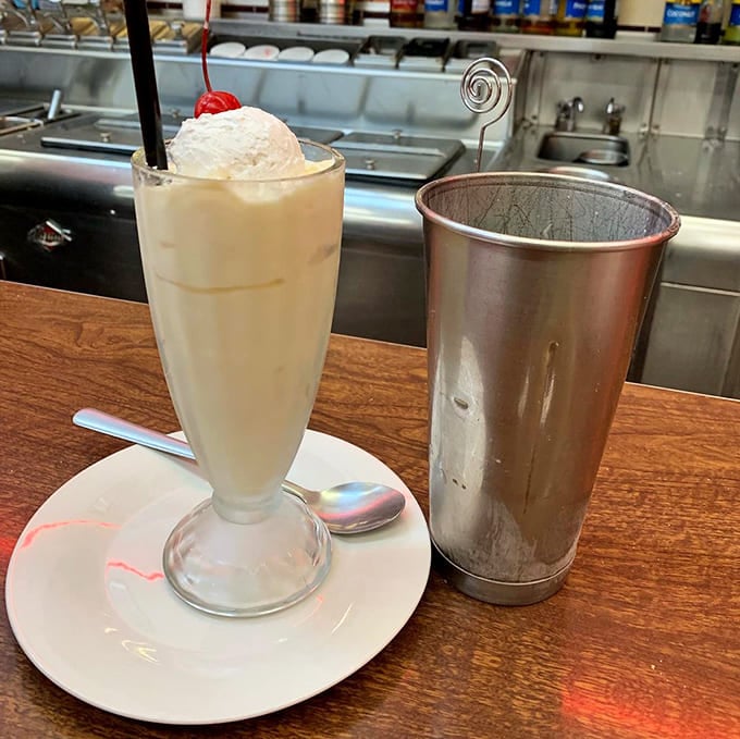The vanilla milkshake arrives with its metal mixing cup sidekick—that little extra portion that makes you feel like you've gotten away with something delicious.