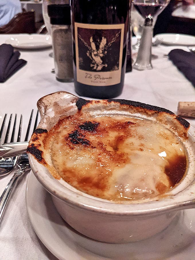 The French onion soup arrives like a bubbling cauldron of cheese-capped comfort that makes you question all other soups.