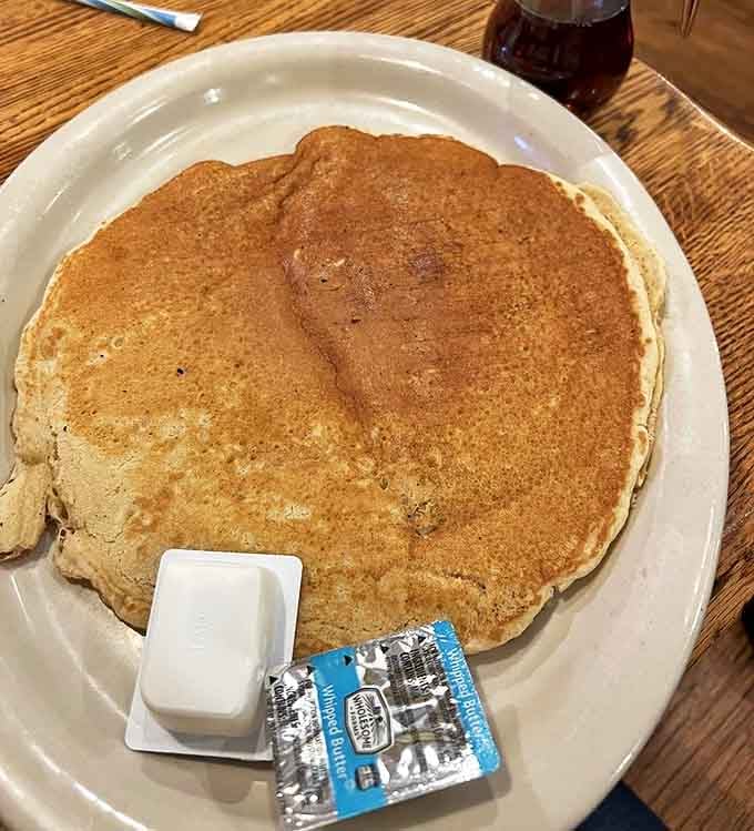This pancake doesn't just hang over the edge of the plate &ndash; it has its own zip code. Golden, fluffy, and ready to soak up rivers of syrup.