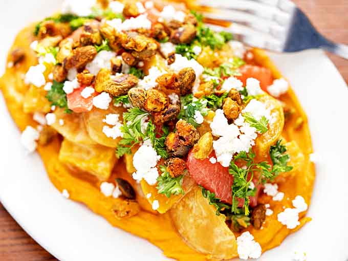 Sweet potato waffle perfection: where crispy edges meet pillowy centers under a crown of savory toppings and fresh herbs.
