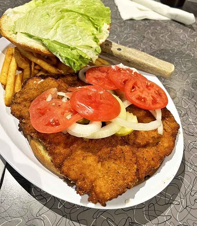 The tenderloin sandwich that launched a thousand road trips. That golden-brown breading hanging gloriously over the bun is pure Indiana poetry.
