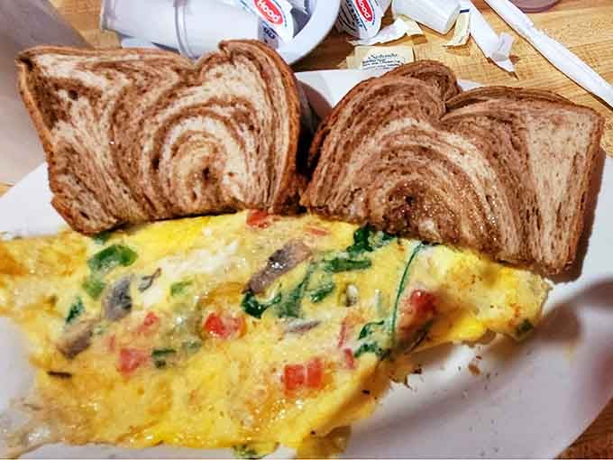 This isn't just any veggie omelet&mdash;it's a masterclass in egg architecture, stuffed with fresh vegetables and paired with perfectly marbled rye toast.