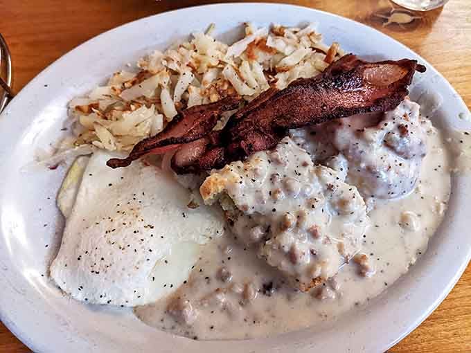 Biscuits smothered in sausage gravy with crispy bacon on top &ndash; the kind of breakfast that makes you want to climb a mountain, or at least take a glorious nap afterward.