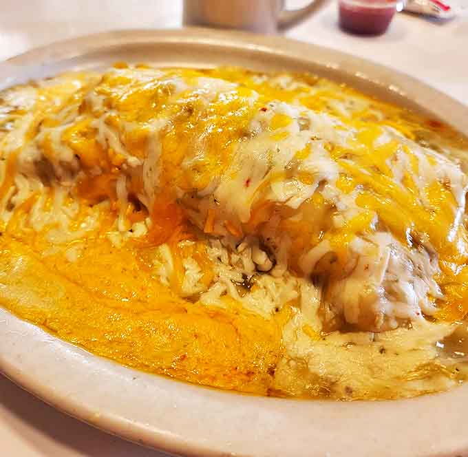 Behold the breakfast burrito in its natural habitat&mdash;smothered in cheese and sauce, challenging the very concept of handheld food. Fork required, no regrets allowed.