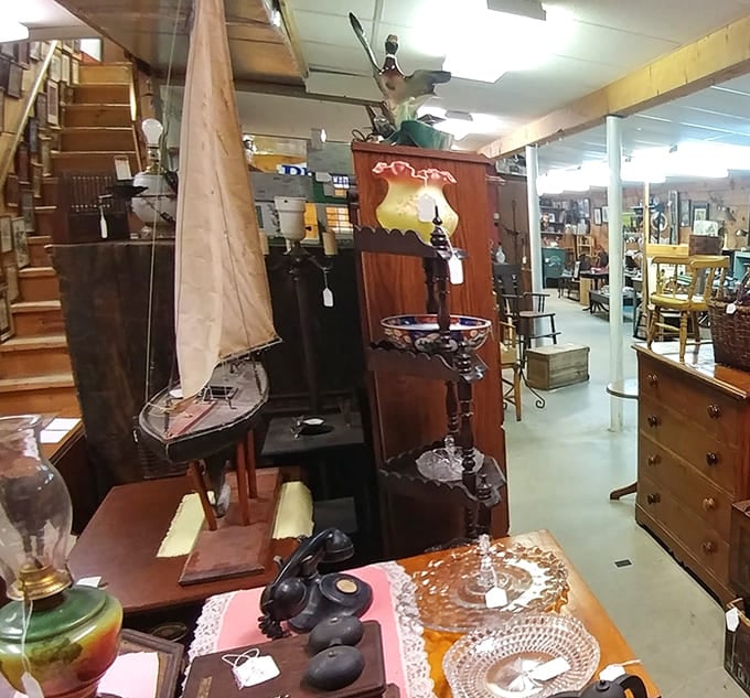 The staircase beckons to upper floors while model sailboats and antique furniture create an impromptu time-travel departure lounge.