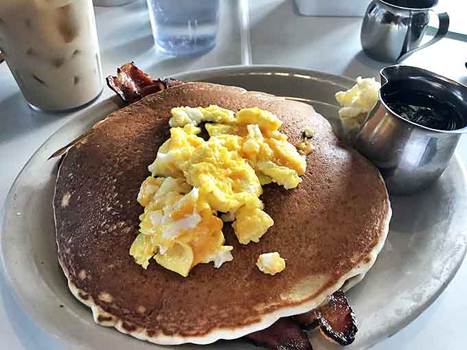 Pancake perfection achieved: a golden disc topped with fluffy scrambled eggs and crispy bacon – the breakfast trifecta in its natural habitat.