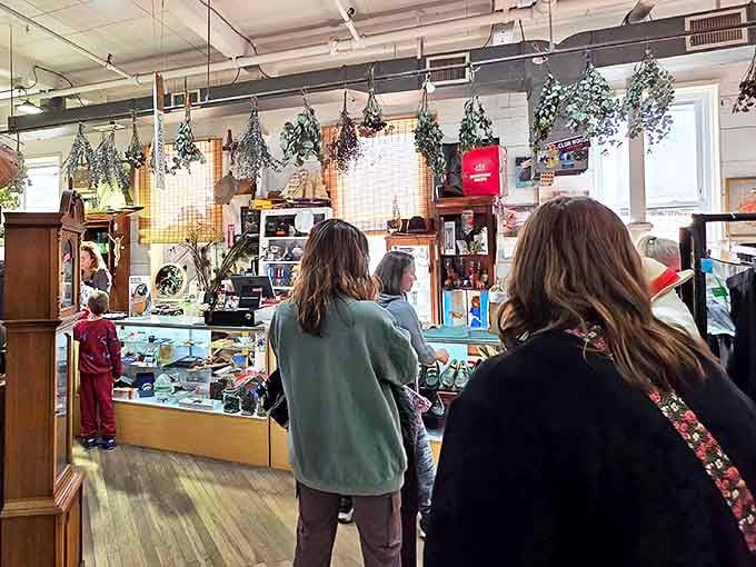 The checkout counter buzzes with activity as shoppers bring their finds forward, dried herbs hanging from above like nature's own price tags.