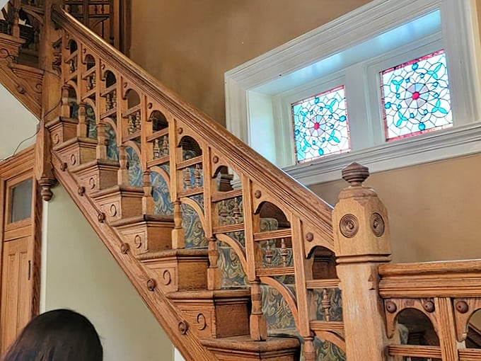 That grand wooden staircase isn't just functional&mdash;it's architectural poetry with ornate details and stained glass that bathes visitors in kaleidoscopic light.