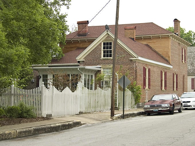 The white picket fence frames this historic home in Ste. Genevieve, where French colonial architecture creates a unique streetscape.