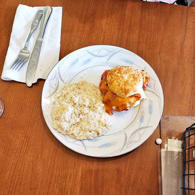 Southern comfort on a plate: a perfectly cooked biscuit crowned with what appears to be a savory topping alongside creamy grits. Grandma would approve.