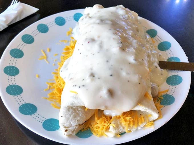 This isn't just a breakfast burrito; it's a gravity-defying monument to morning indulgence, lovingly smothered in creamy sausage gravy.