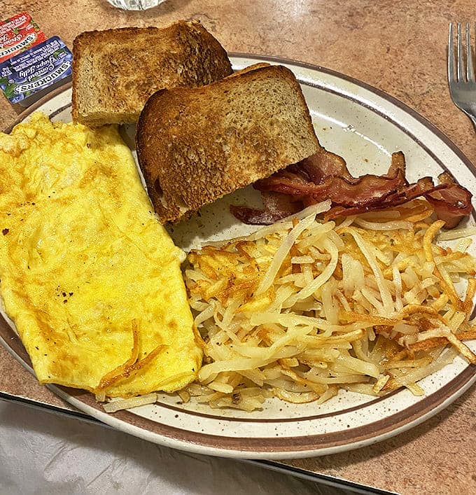 Breakfast perfection: a golden omelet, crispy hash browns, and toast that actually tastes like bread should. Morning fuel that puts chain restaurants to shame.