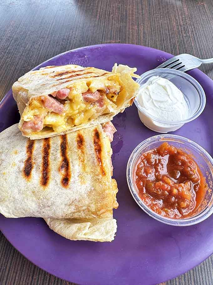 Breakfast burritos: where eggs and cheese find their higher purpose. This grilled masterpiece comes with sides of salsa and sour cream—because options matter, even in paradise.