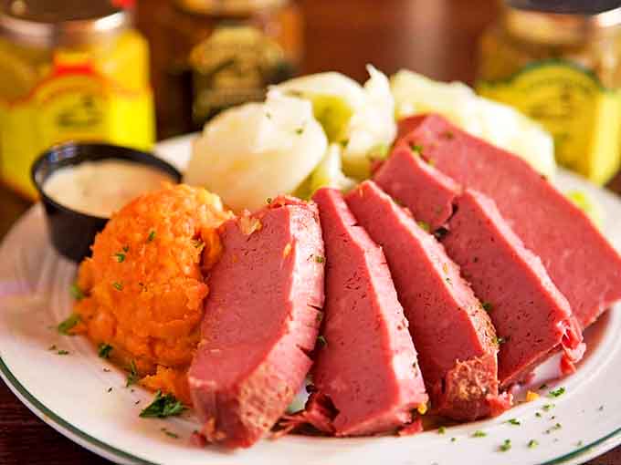 Corned beef sliced so perfectly it could make a New York deli owner weep with joy, accompanied by that vibrant orange side that screams "authentic."