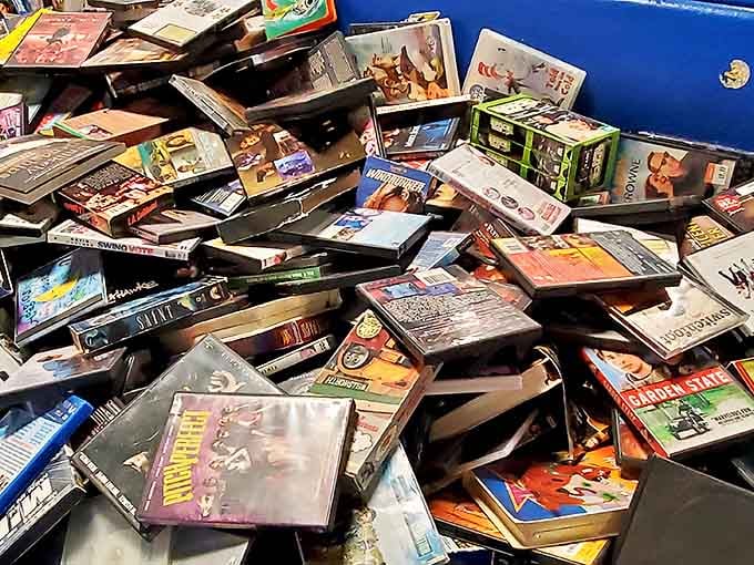 DVDs stacked like geological layers - dig deep enough and you might unearth that obscure 90s film you've been seeking.