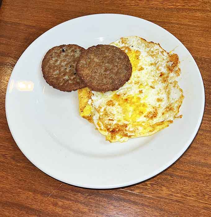 Simple perfection: two perfectly cooked sausage patties alongside sunny-side-up eggs. Sometimes breakfast doesn't need to overthink things.