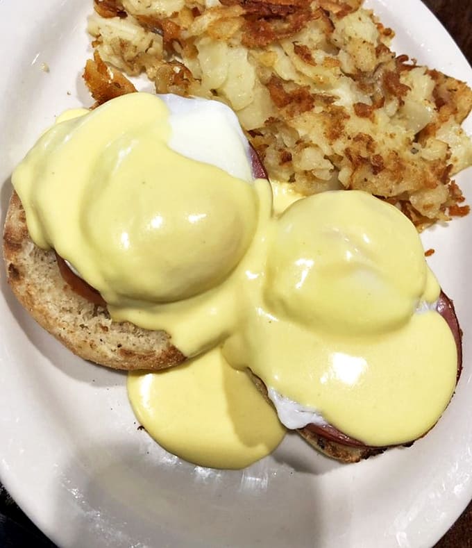 Eggs Benedict done right&mdash;hollandaise cascading down like a yellow waterfall, meeting crispy home fries in perfect harmony.