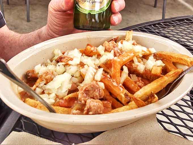 Green chile fries wearing a blanket of diced onions like the world's most welcoming comfort food avalanche.